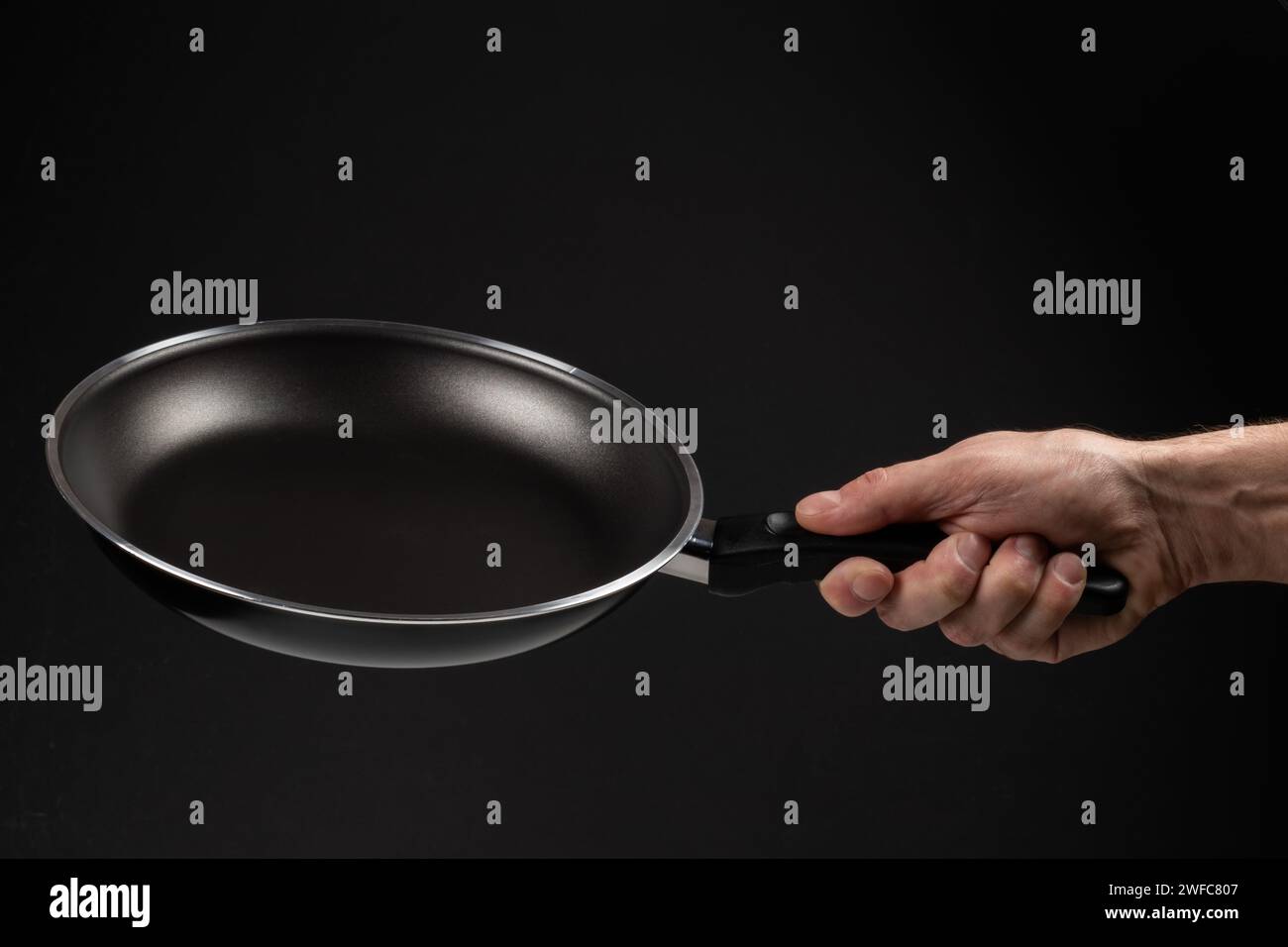 hand holding Frying pan on dark background Stock Photo - Alamy