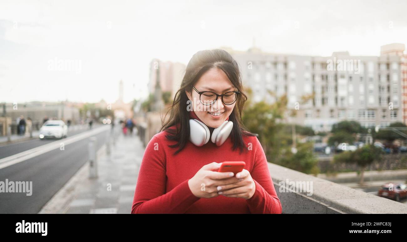 Asian girl using mobile phone while walking around city on cloudy day ...