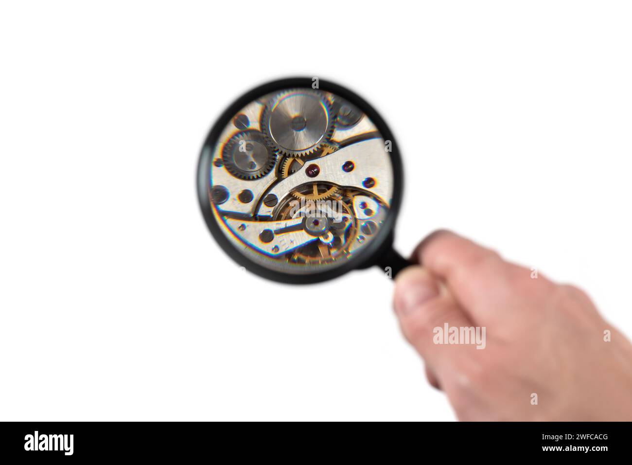 A man examines the mechanism of a old watch through a magnifying glass ...