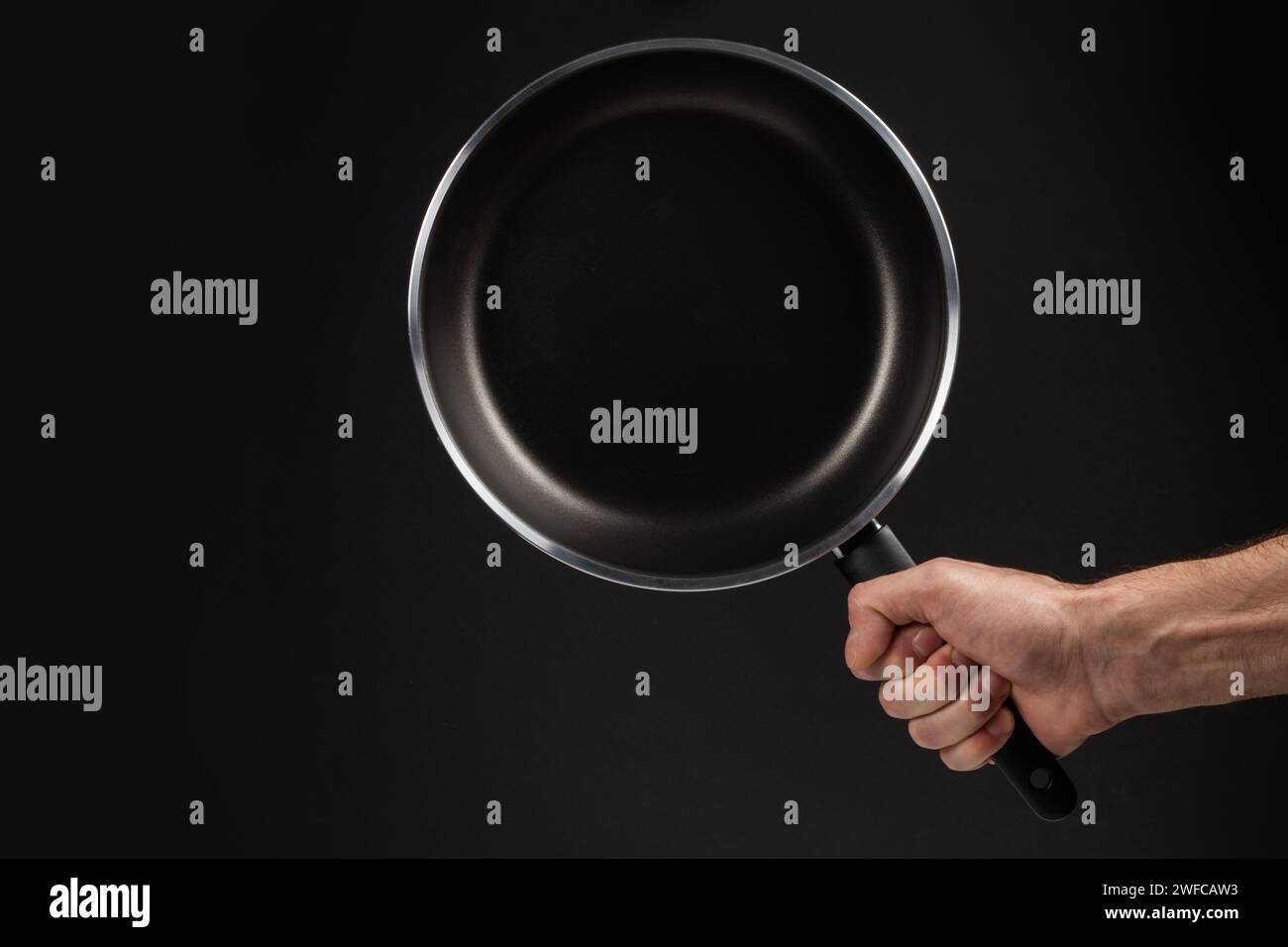 hand holding Frying pan on dark background Stock Photo - Alamy