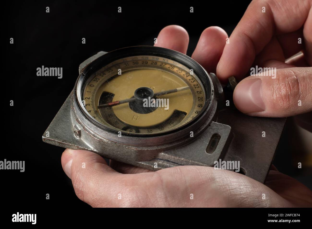 Old mining compass in hand on dark background close up Stock Photo - Alamy