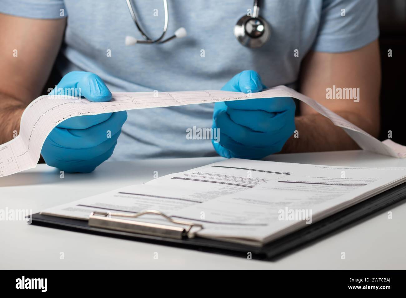 Doctor's hands hold result of the cardiogram next to patient sitting ...