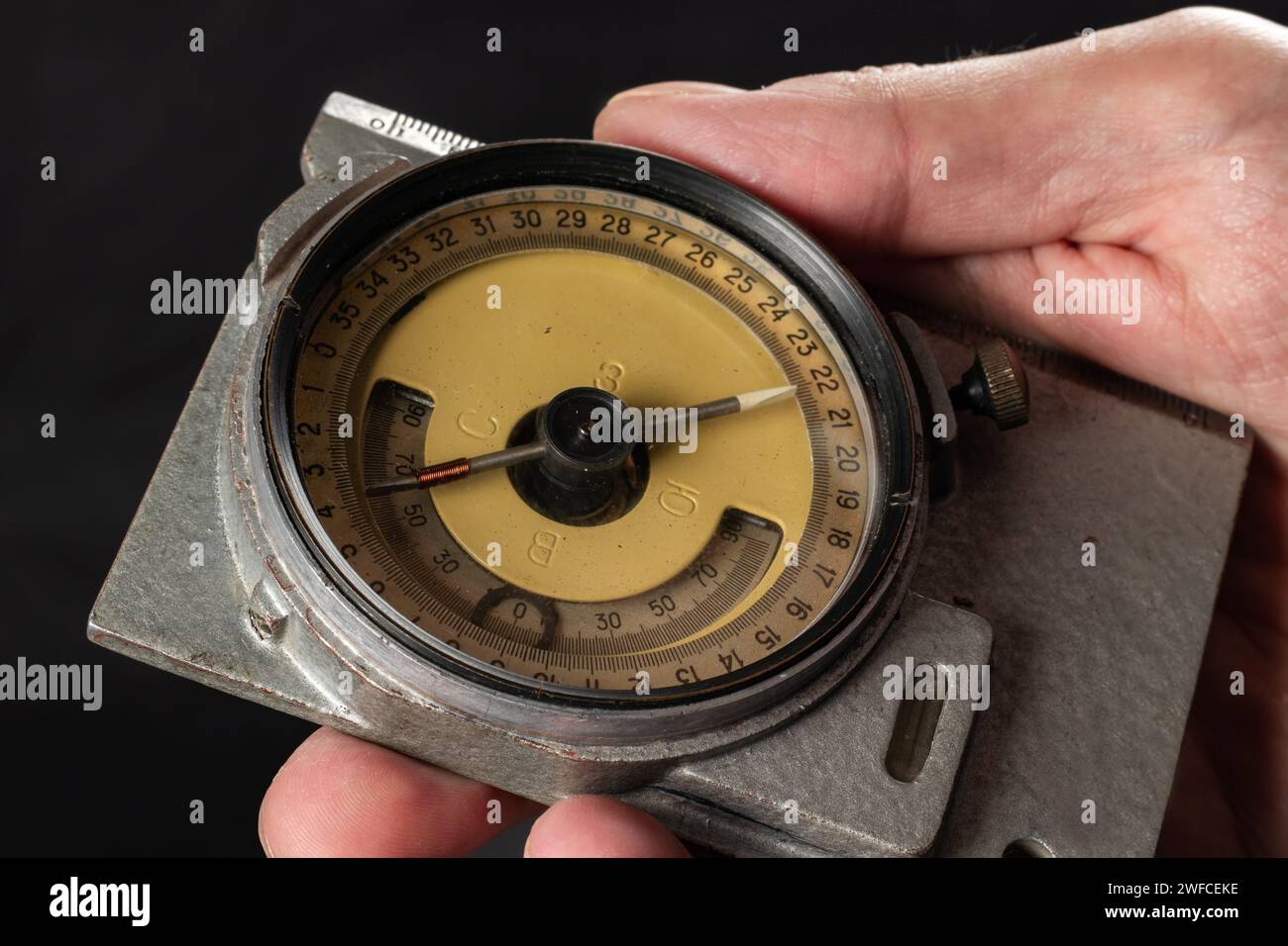 Old mining compass in hand on dark background close up Stock Photo - Alamy