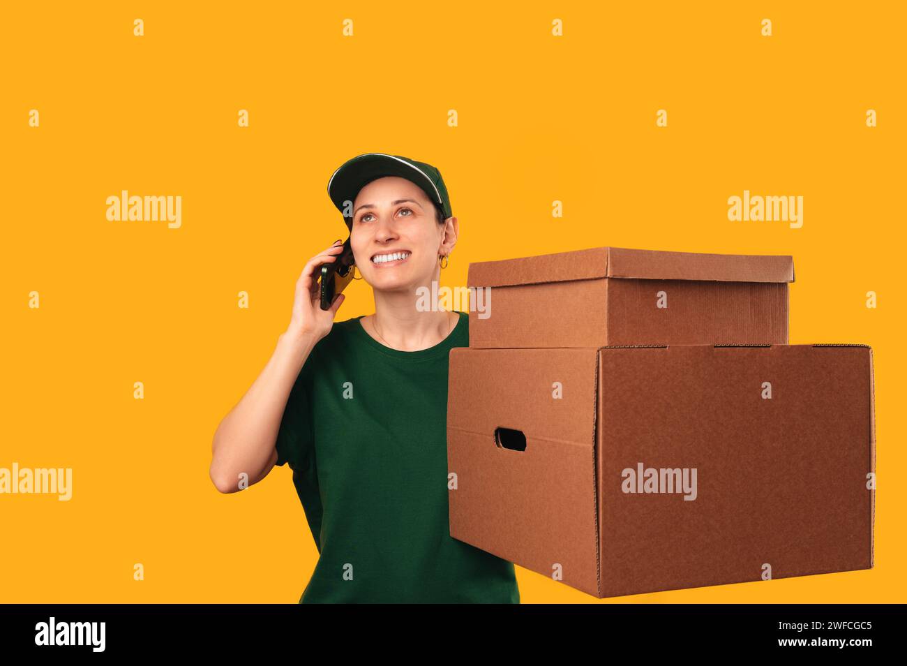 Young cheerful woman wearing green uniform is holding some delivery ...