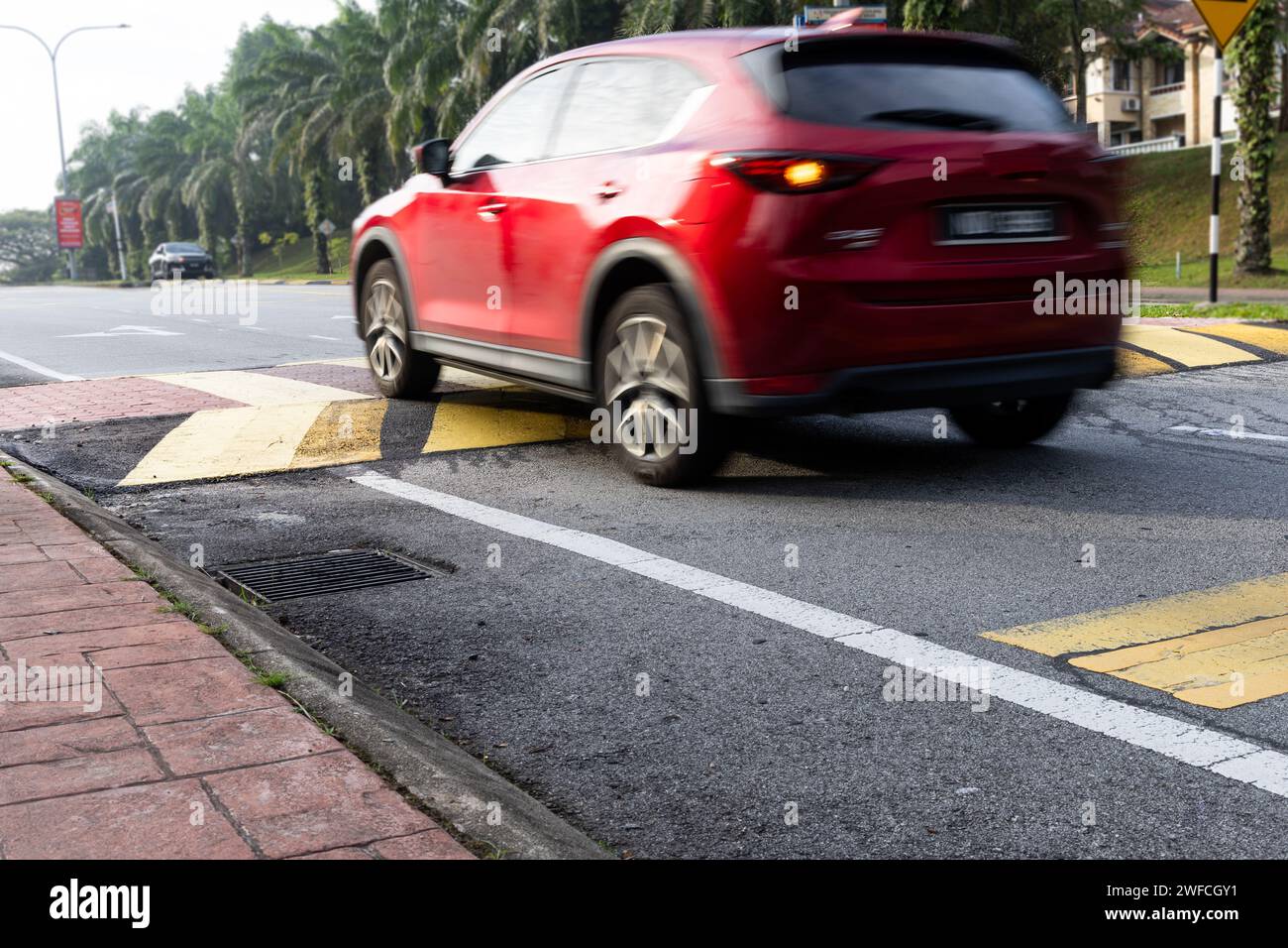 Car slowing down at speed bump or road hump painted in yellow and black ...