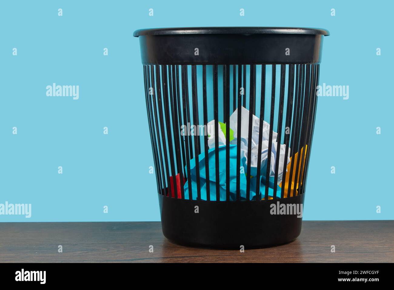 Crumpled paper in the trash can on blue background Stock Photo - Alamy