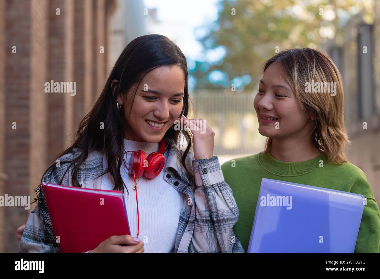 Smiling multiracial college student friends looking at notes, talking ...
