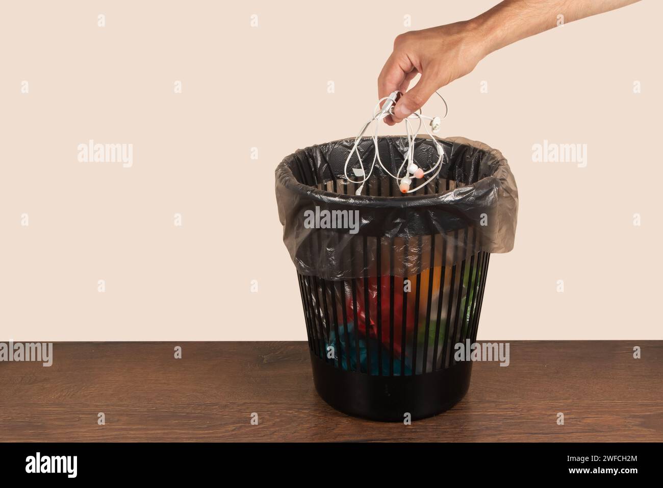 Hand throwing old shabby decrepit headphones away, trash bin ...