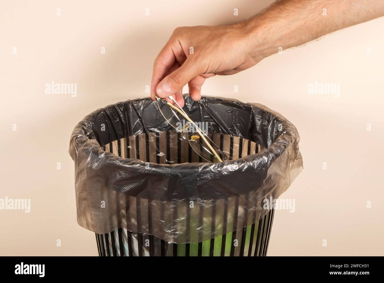 throw glasses in trash bin, glasses in hand in front of trash can ...