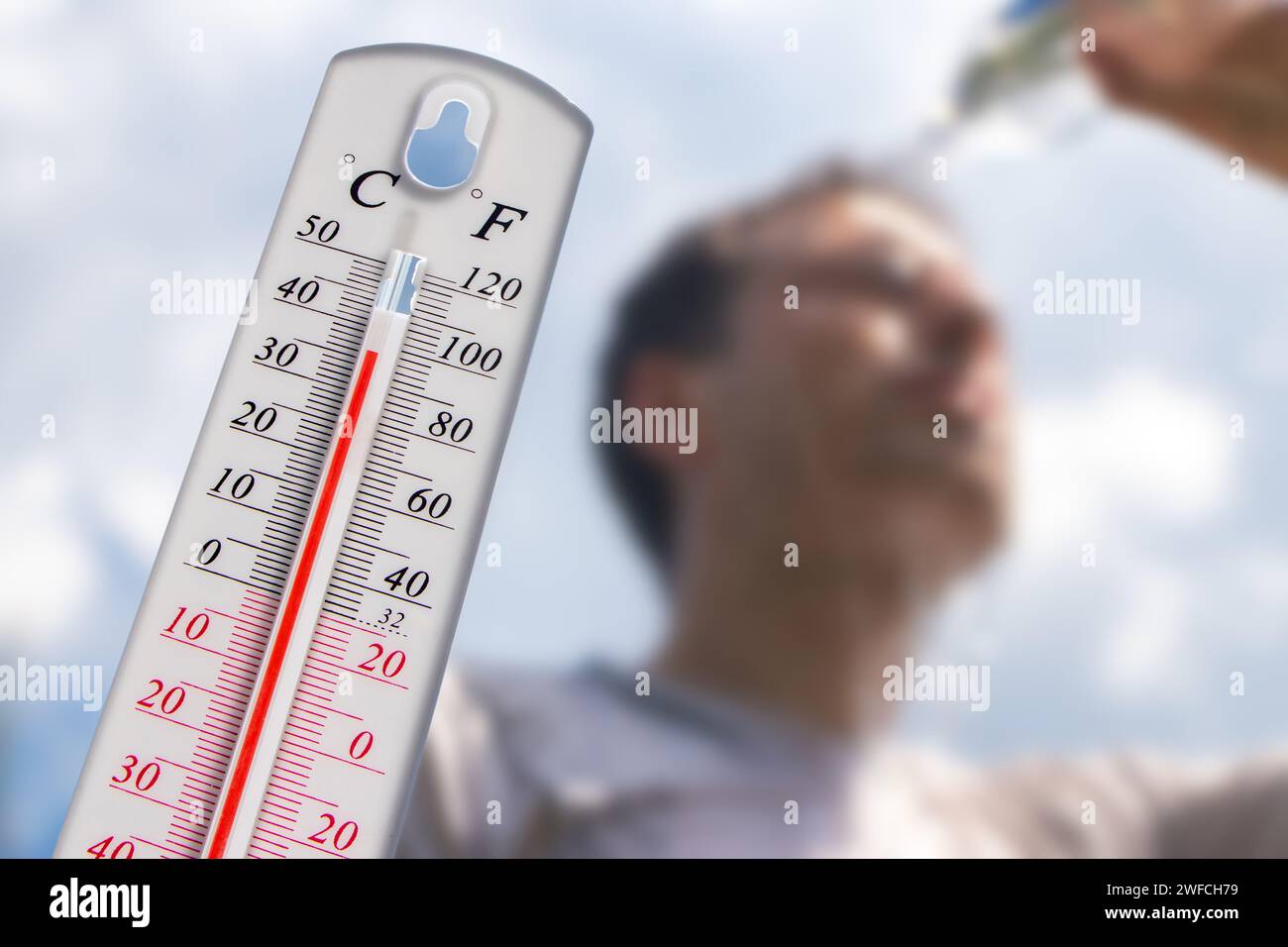 Man pouring water on his head in extreme heat. Thermometer in summer ...