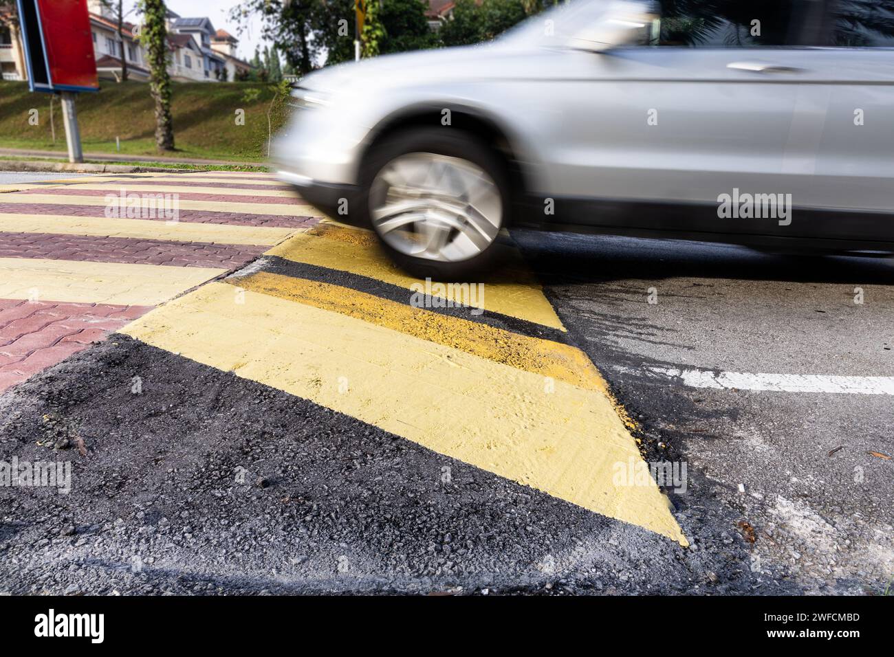 Car slowing down at speed bump or road hump painted in yellow and black ...