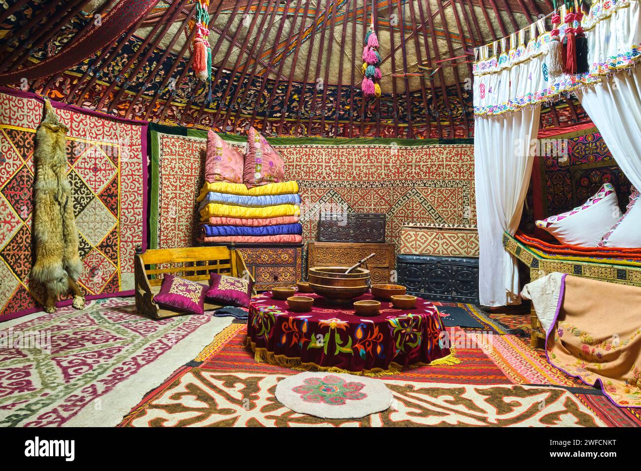 Interior view of a traditional yurt, filled with family blankets, rugs, textiles, chests, a bed ...