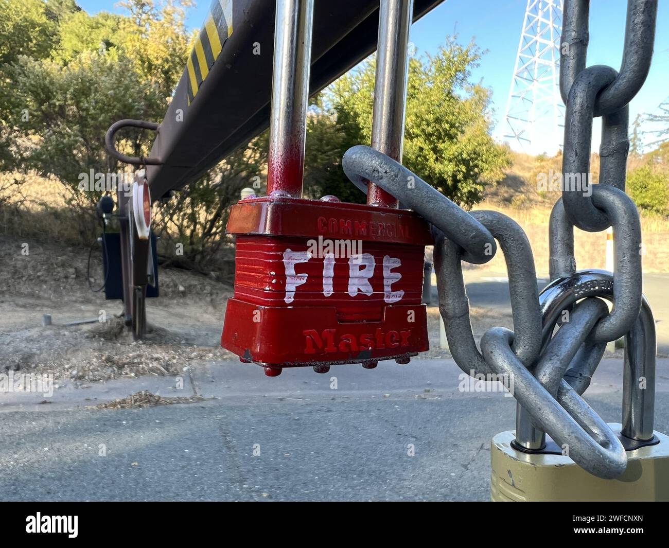 Red fire trail lock at a trailhead, with natural backdrop and partial ...