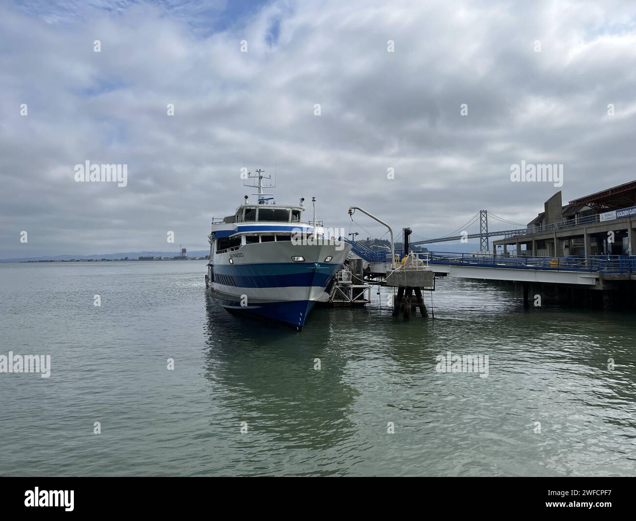 A ferry docked at Harry Bridges Plaza with a view of the Bay Bridge in ...