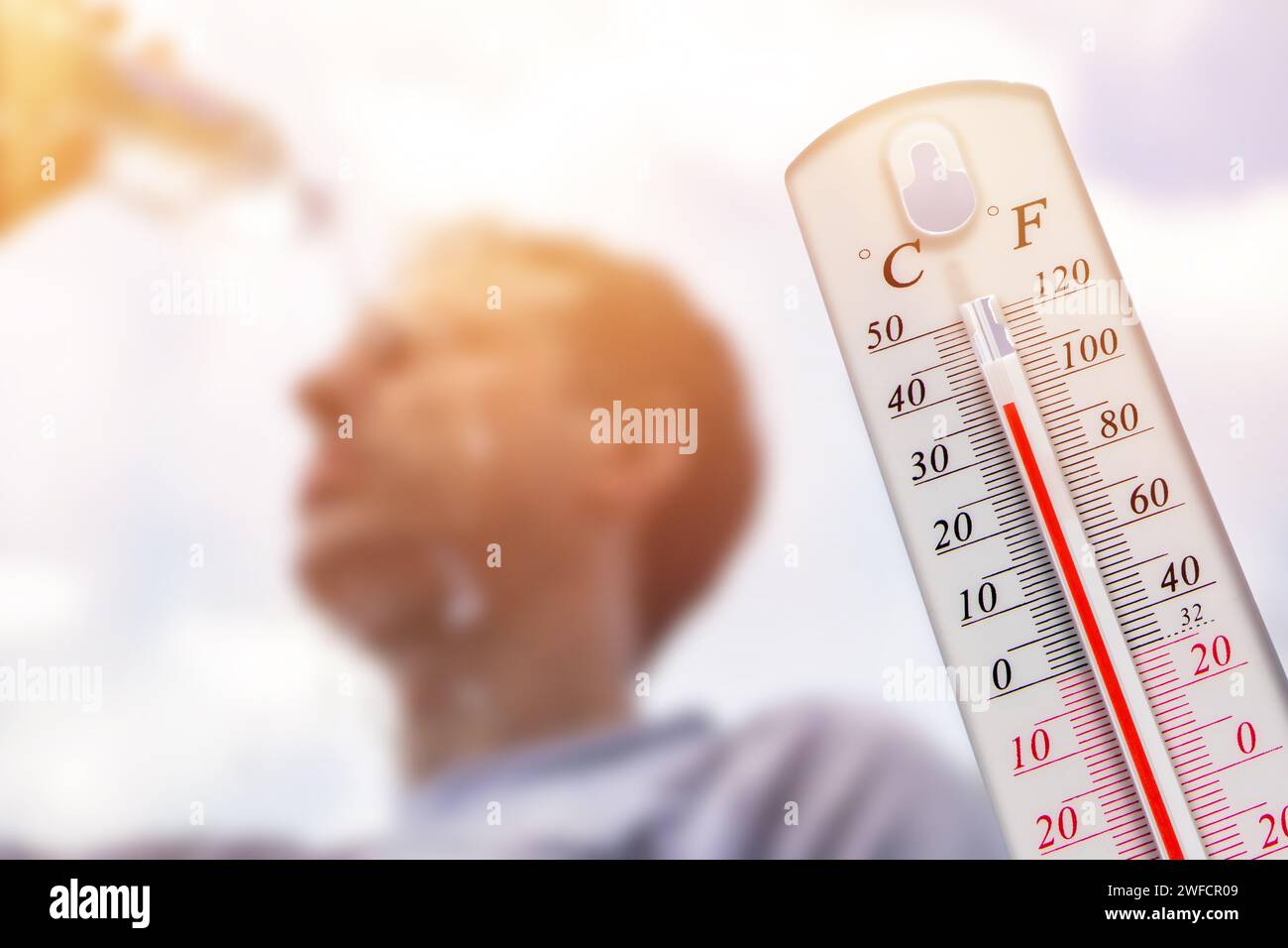 Man pouring water on his head in extreme heat. Thermometer in summer ...