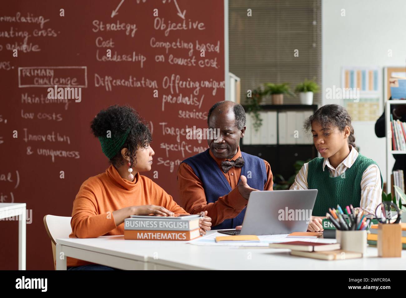 Front view portrait of senior Black teacher talking to students at ...