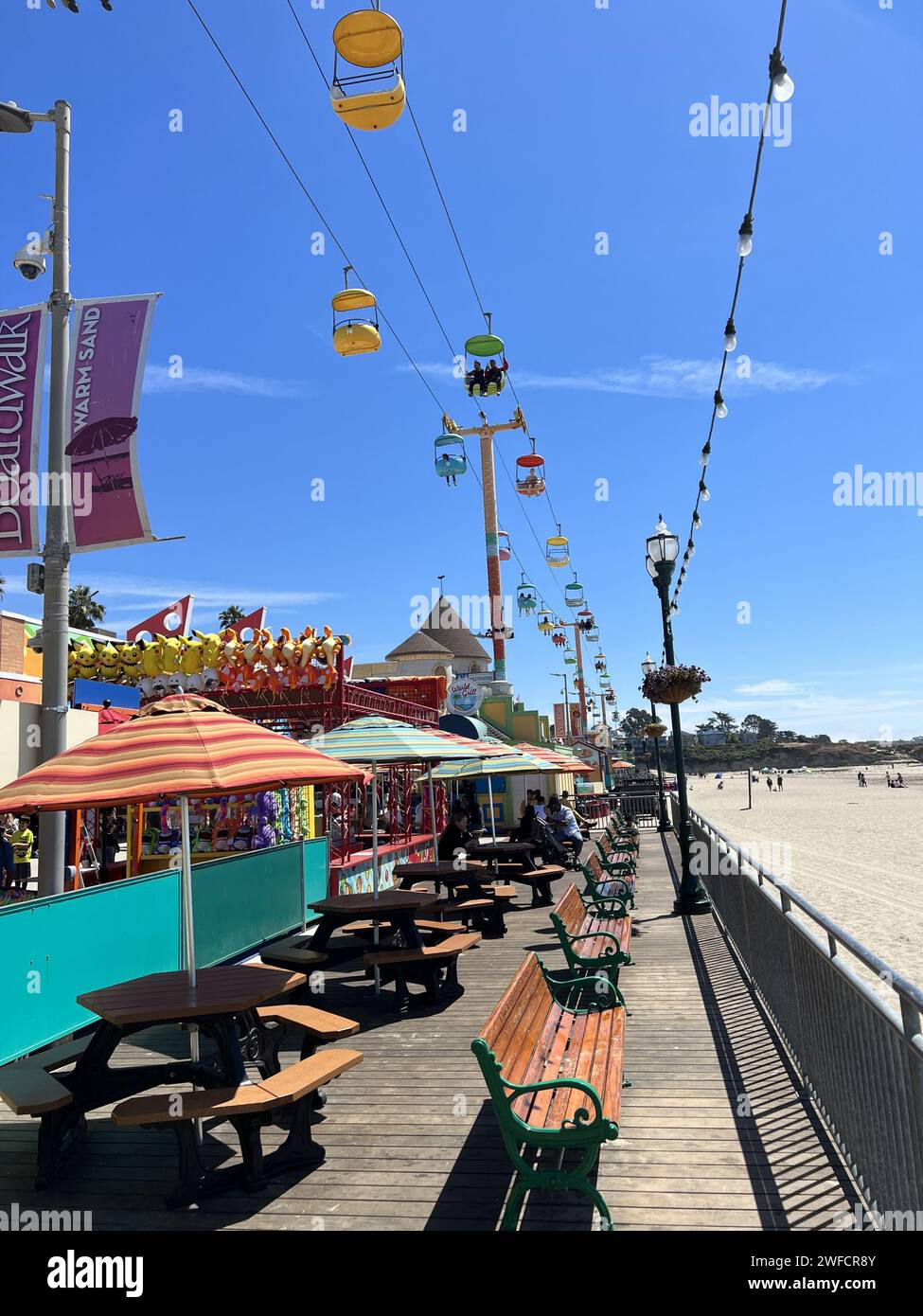 Vibrant skyglider ride above boardwalk with visitors enjoying seaside ...