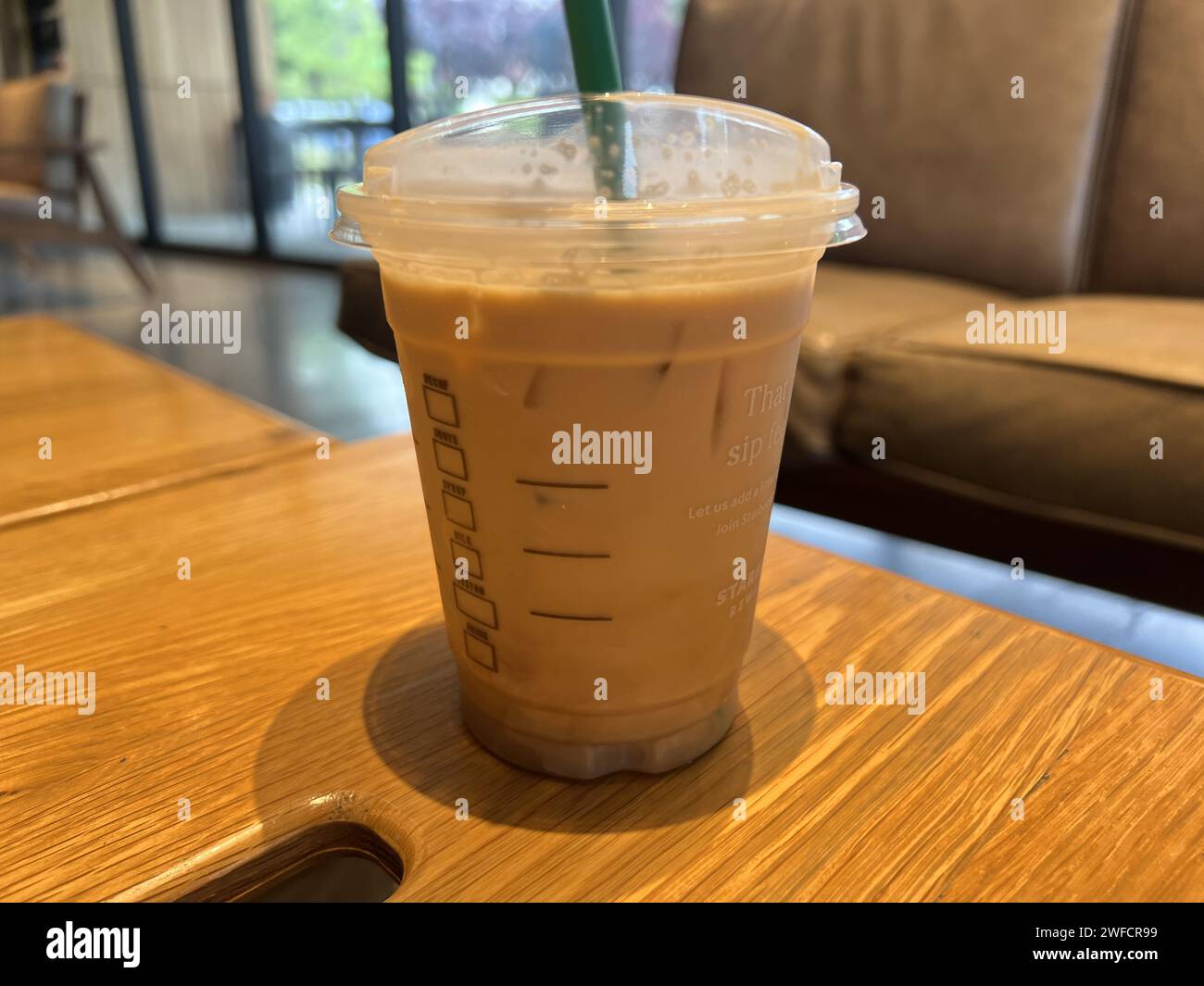 Iced coffee beverage in a clear plastic cup on a wooden table inside a ...