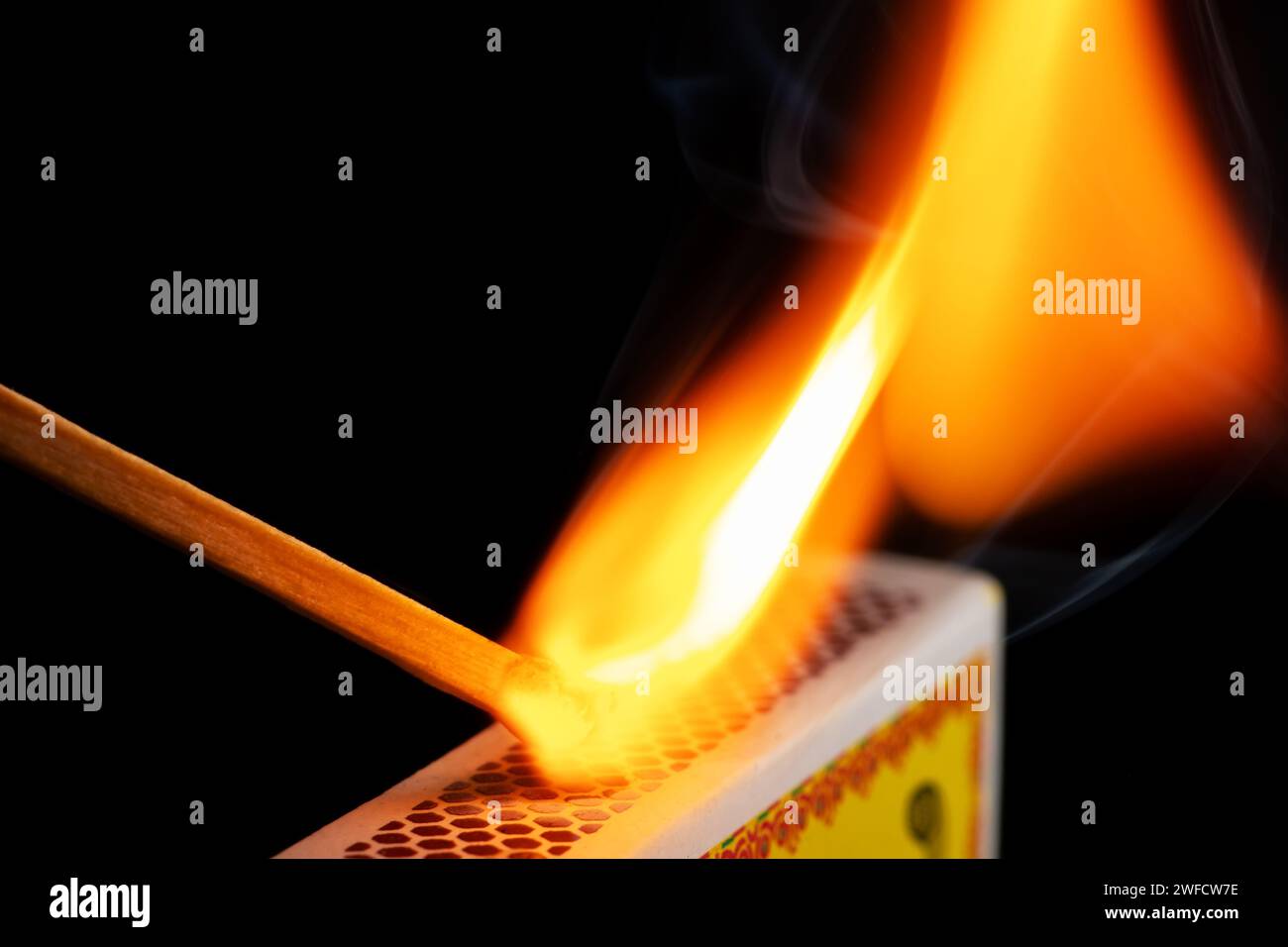 A matchstick lights after it is struck agains the flint surface of a ...