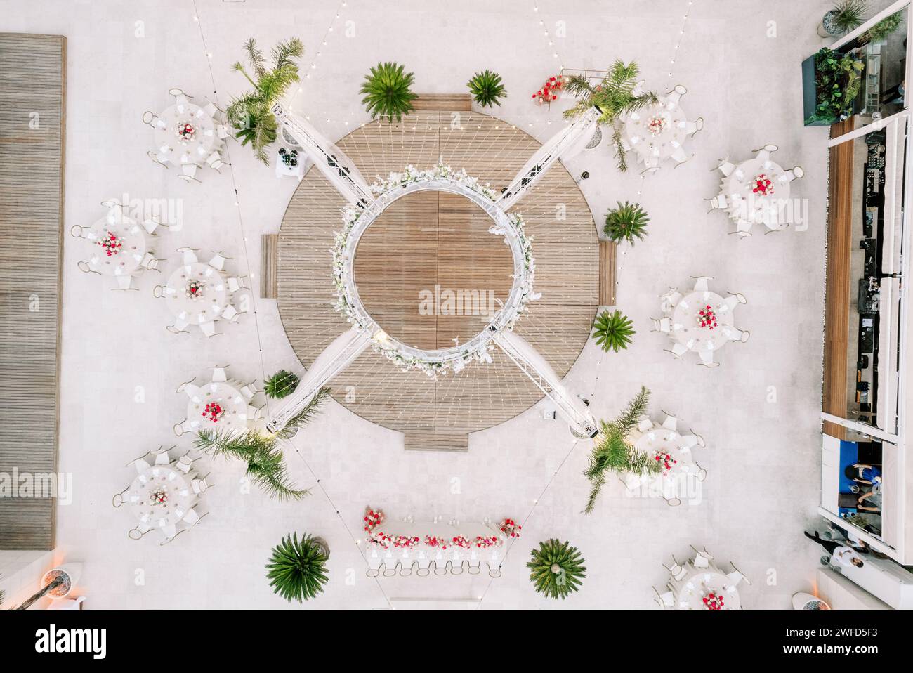 Festive laid tables stand around the stage with a round canopy with ...