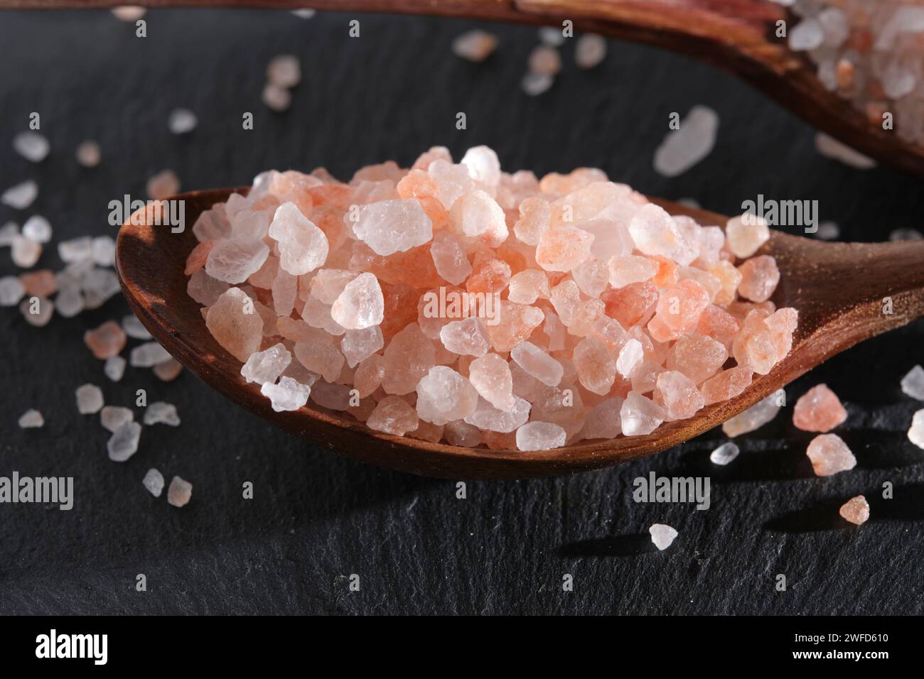 Two wooden spoons lying on a slate are filled with pink salt Stock ...