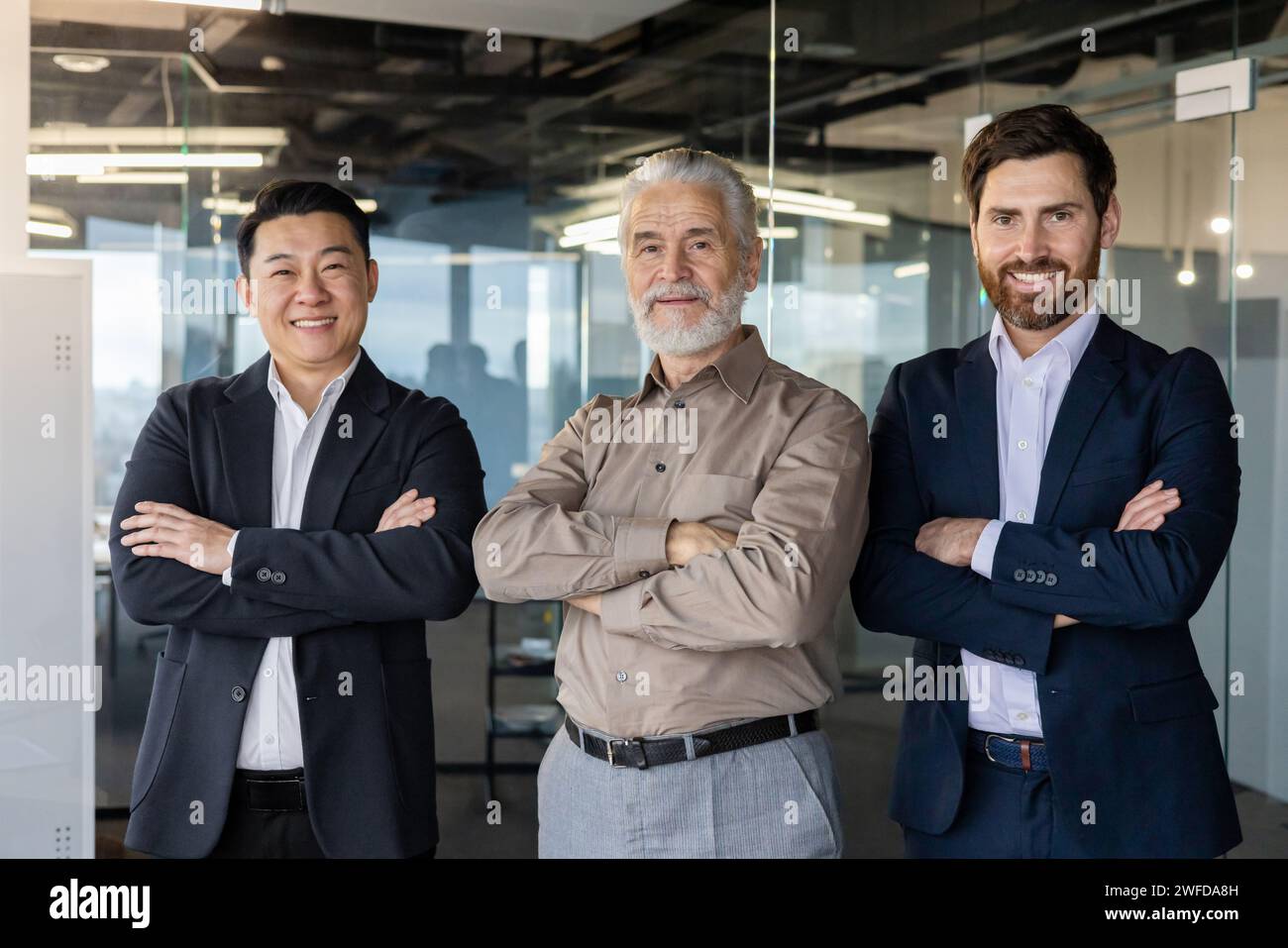 Three confident male professionals standing together with arms crossed ...