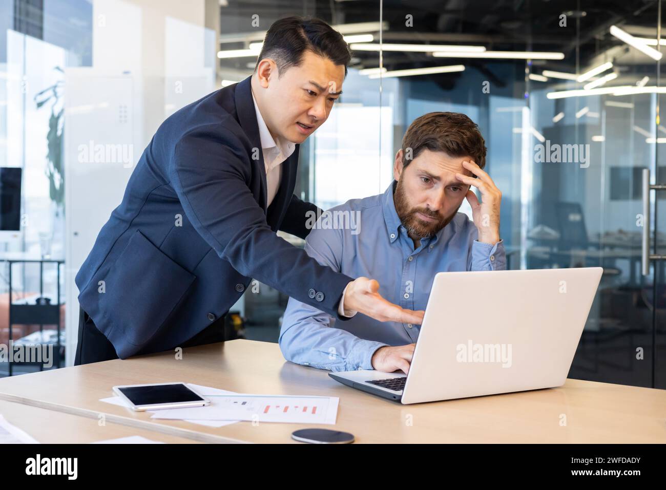 Two corporate professionals working together to resolve an issue, in a ...