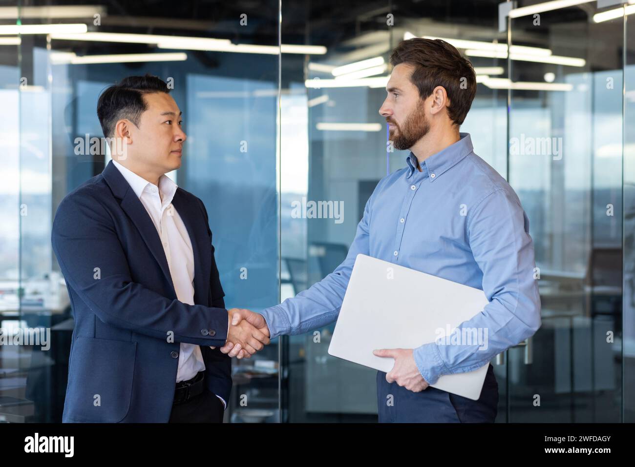 Two professional businessmen shake hands in a corporate office ... Two professional businessmen shake hands in a corporate office ...