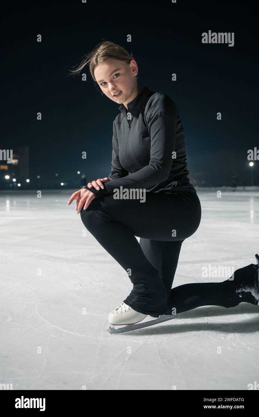 Beautiful young woman ice skating and performing short program over ...