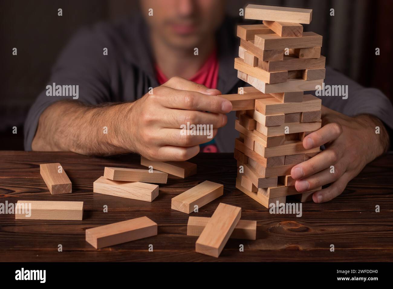Hand of engineer playing a blocks wood tower game on blueprint or ...