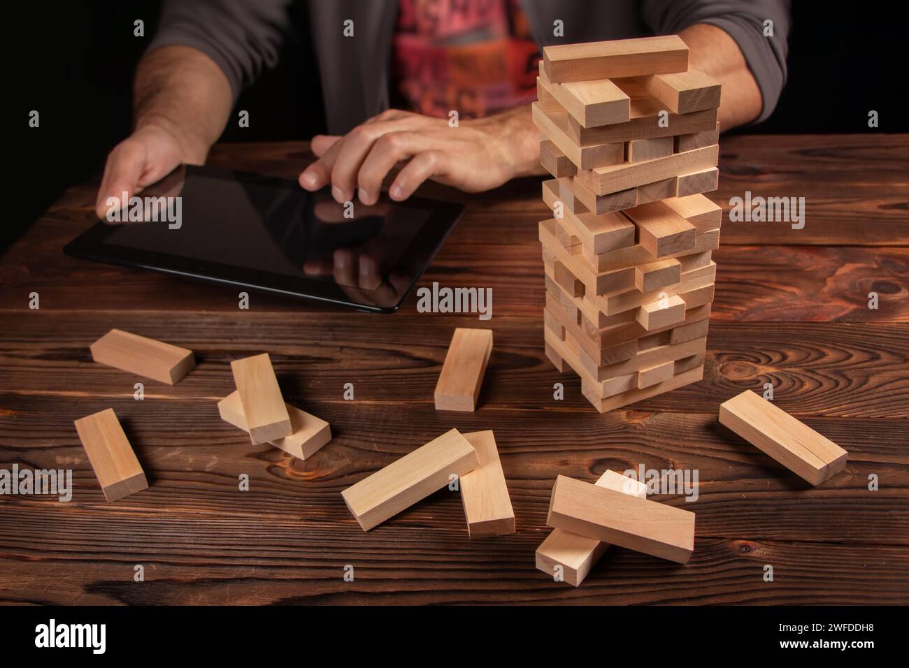 Hand of engineer playing a blocks wood tower game jenga on blueprint or ...