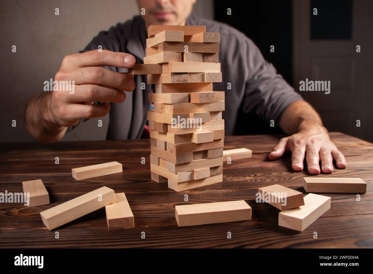 Hand of engineer playing a blocks wood tower game on blueprint or ...