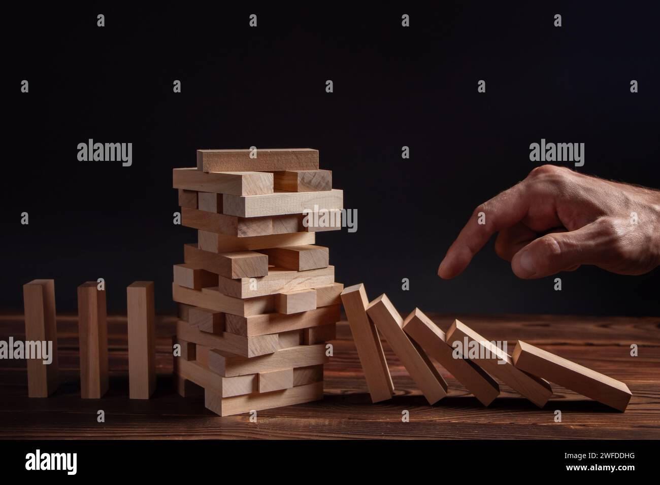 Close-up of fingers pushing a wooden Jenga block with financial risk ...