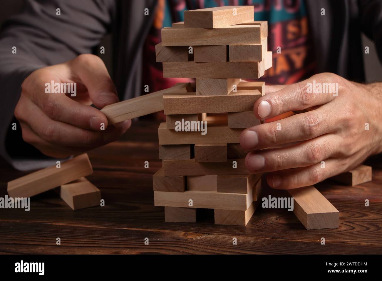 Hand of engineer playing a blocks wood tower game on blueprint or ...