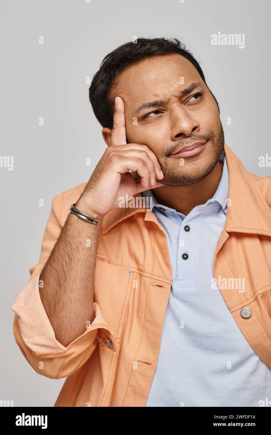 focused indian man in bright orange jacket posing actively and looking ...