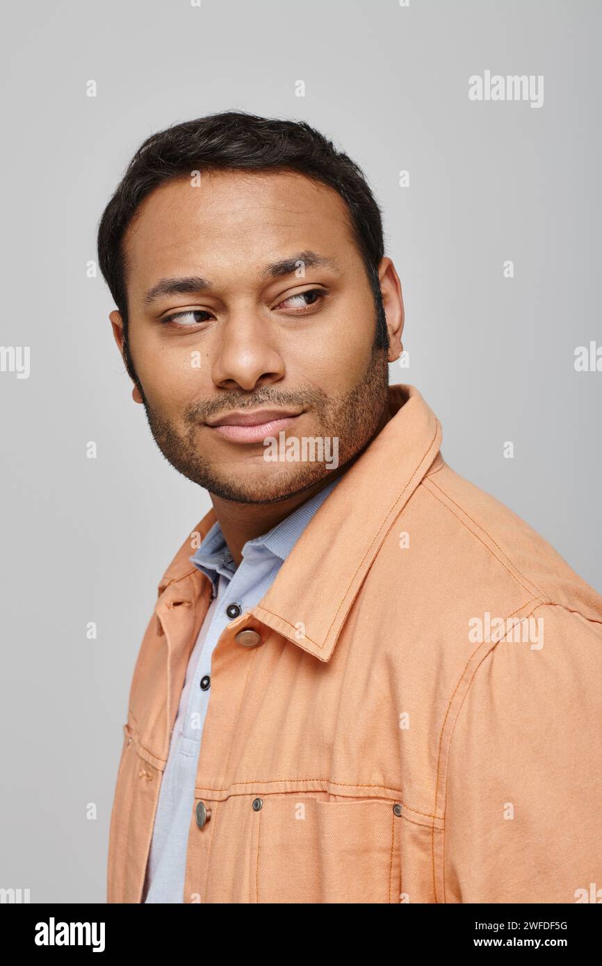 joyous indian man in vivid orange jacket smiling happily and looking ...