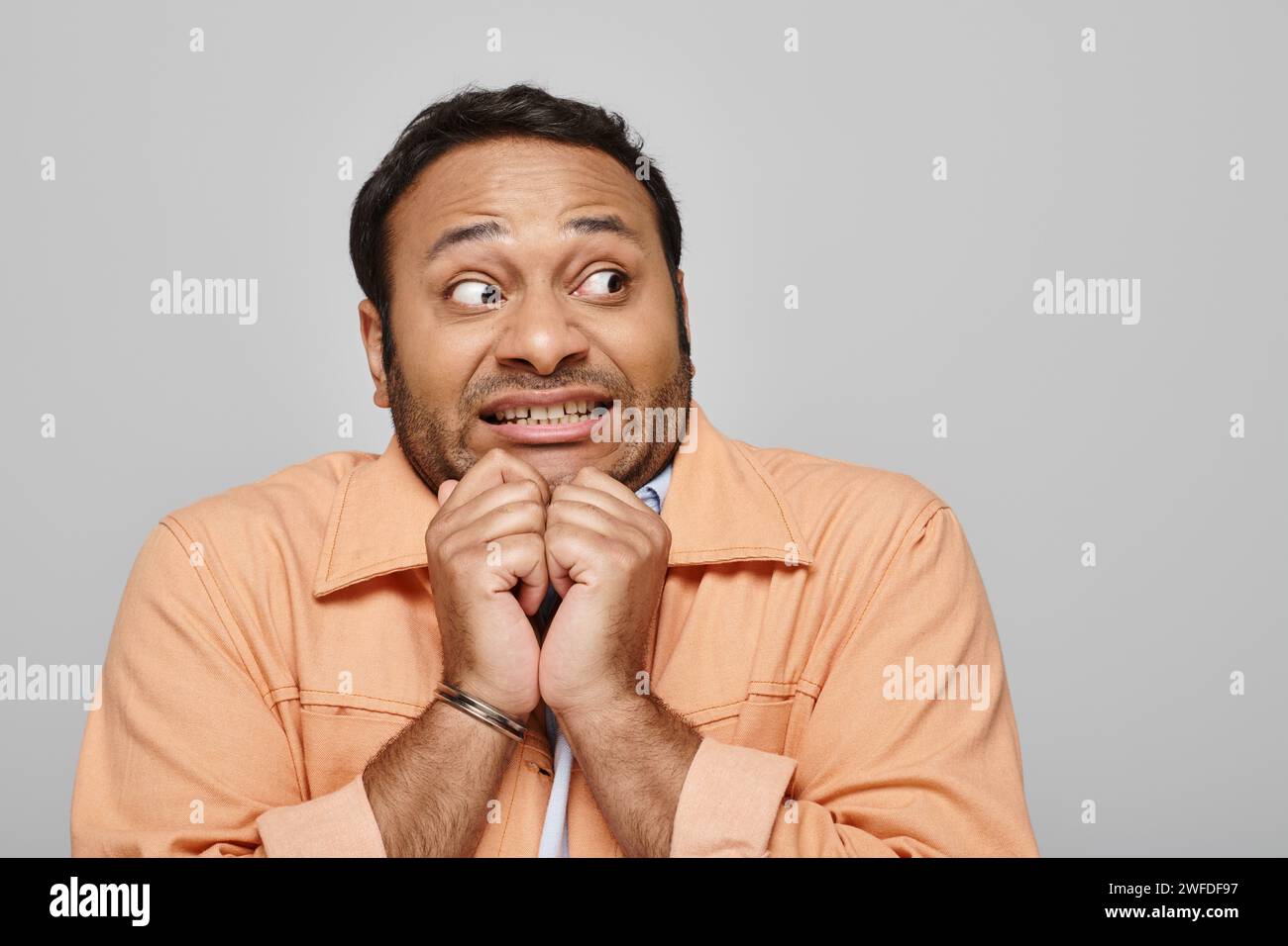 scared indian man in bright orange jacket posing frightened and looking ...