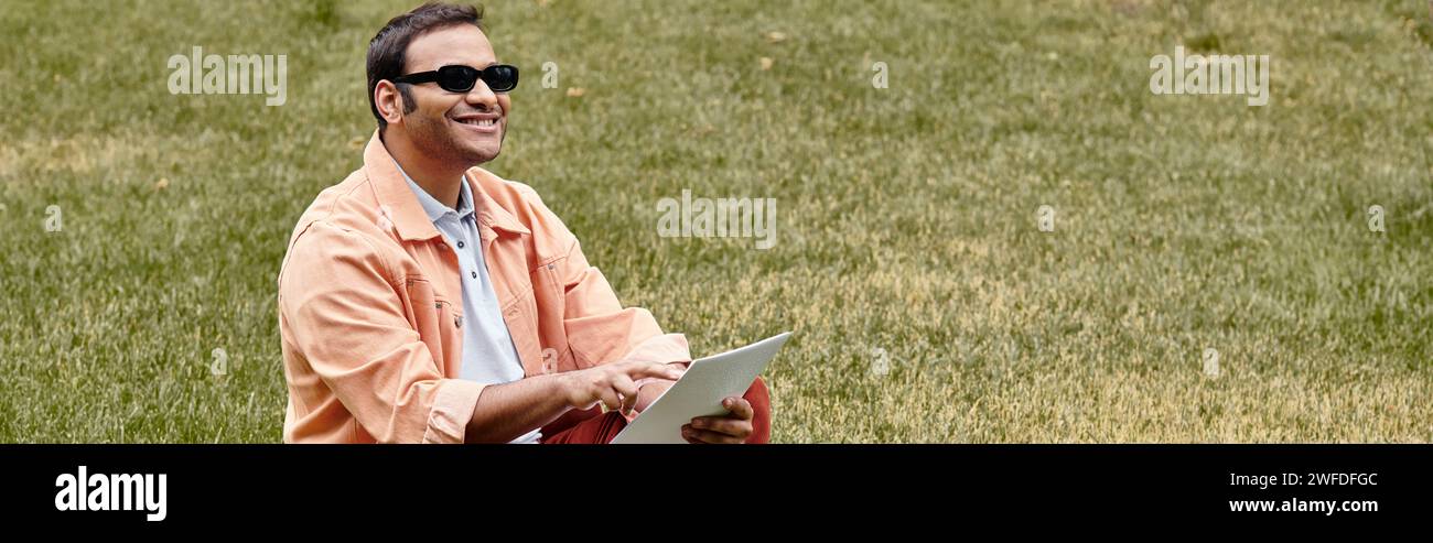 happy indian blind man in jacket sitting on grass with glasses and ...