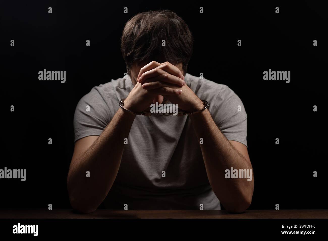 Handcuffed man covering his face with his hands. Arrested and ...