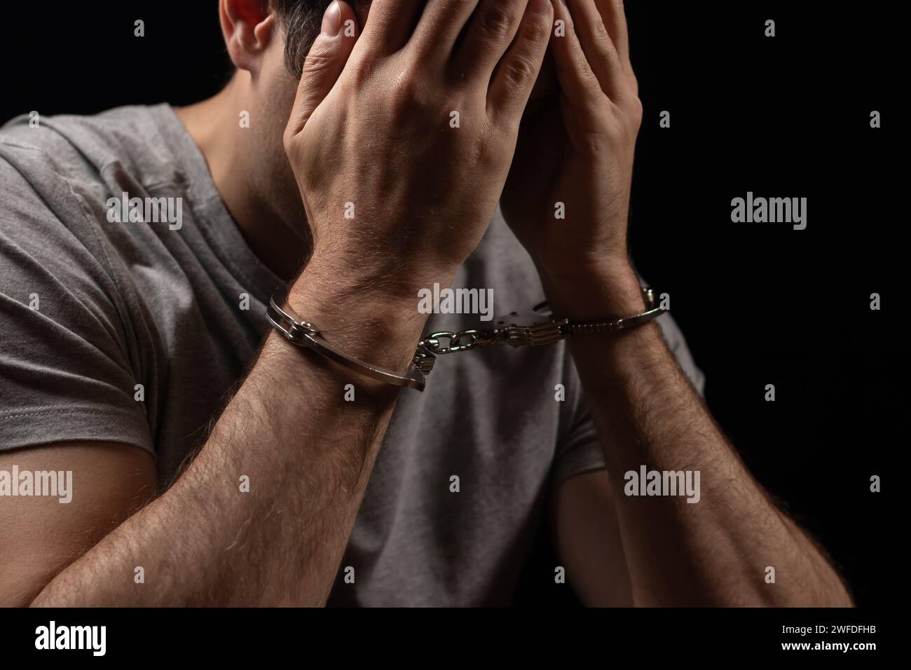 Handcuffed man covering his face with his hands. Arrested and ...