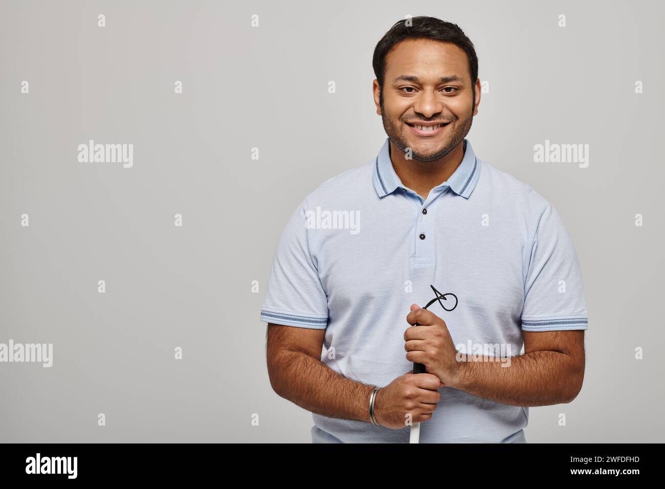 cheerful indian disabled man in blue tee shirt holding walking stick ...