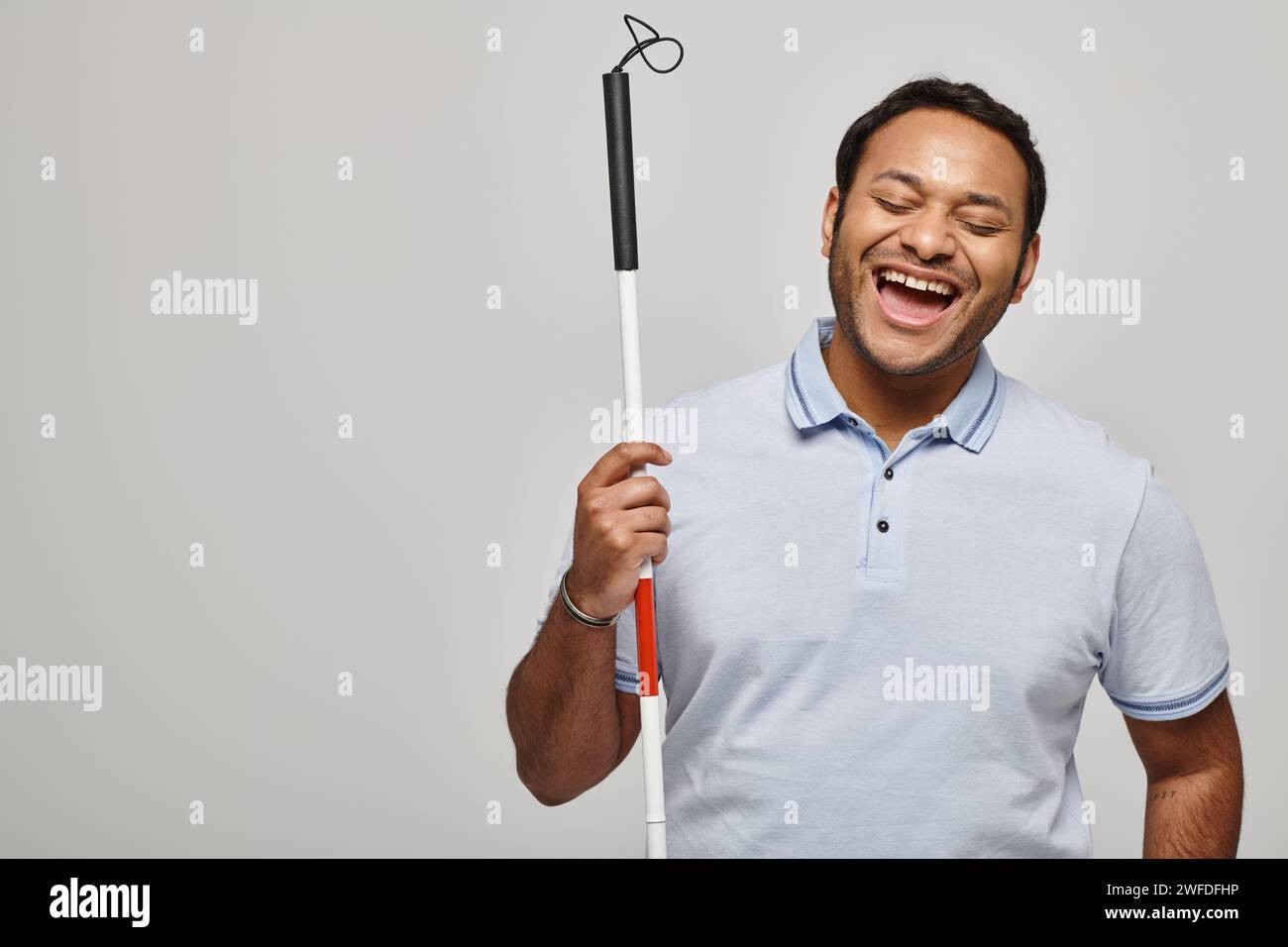 happy indian disabled man in blue tee shirt holding walking stick and ...