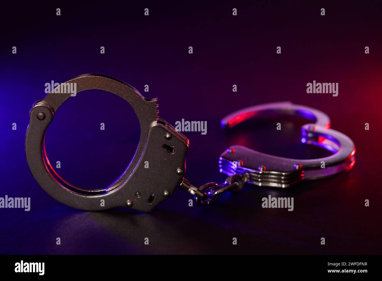 Closed handcuffs on the street pavement at night with police car lights ...