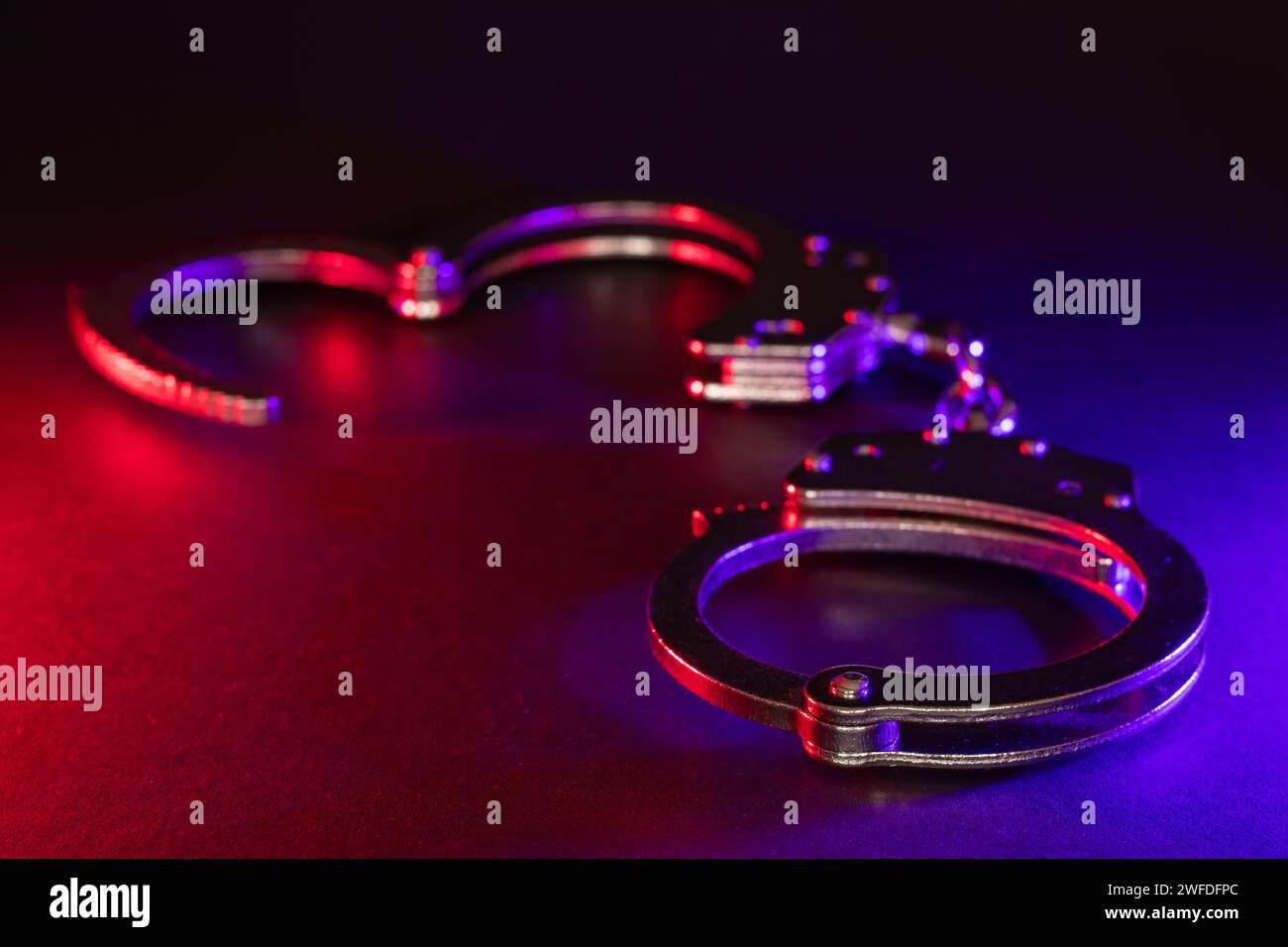 Closed handcuffs on the street pavement at night with police car lights ...