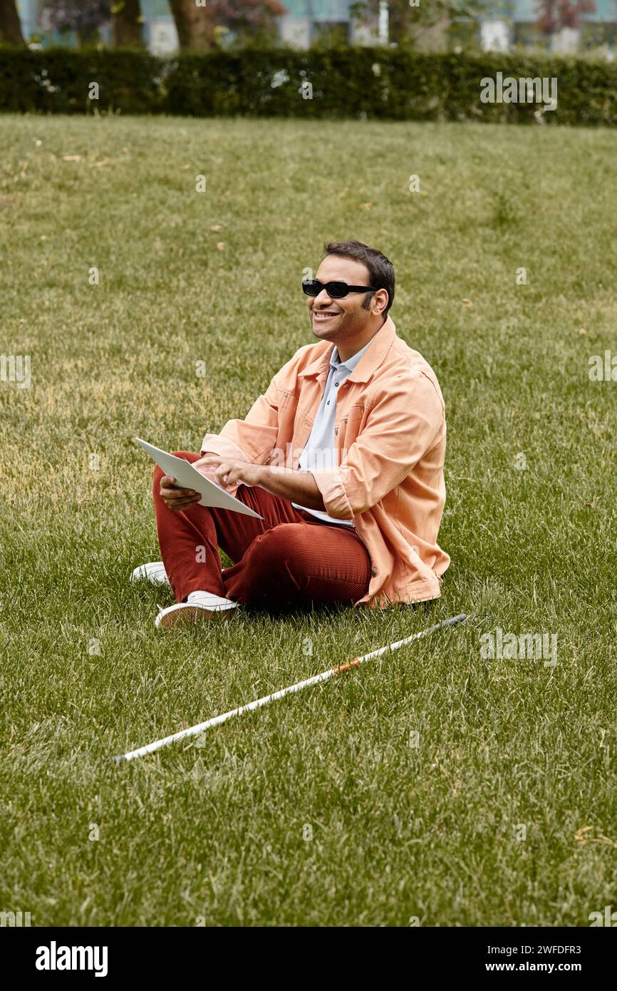 jolly indian blind man in orange vivid jacket sitting on grass with ...
