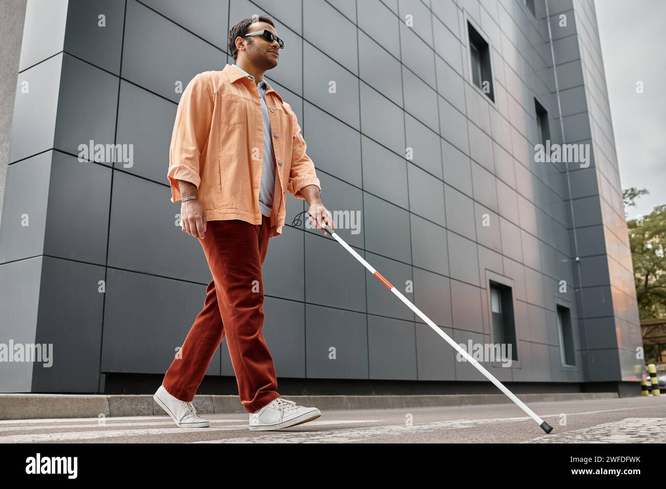 glad indian blind man in orange jacket with walking stick and glasses ...