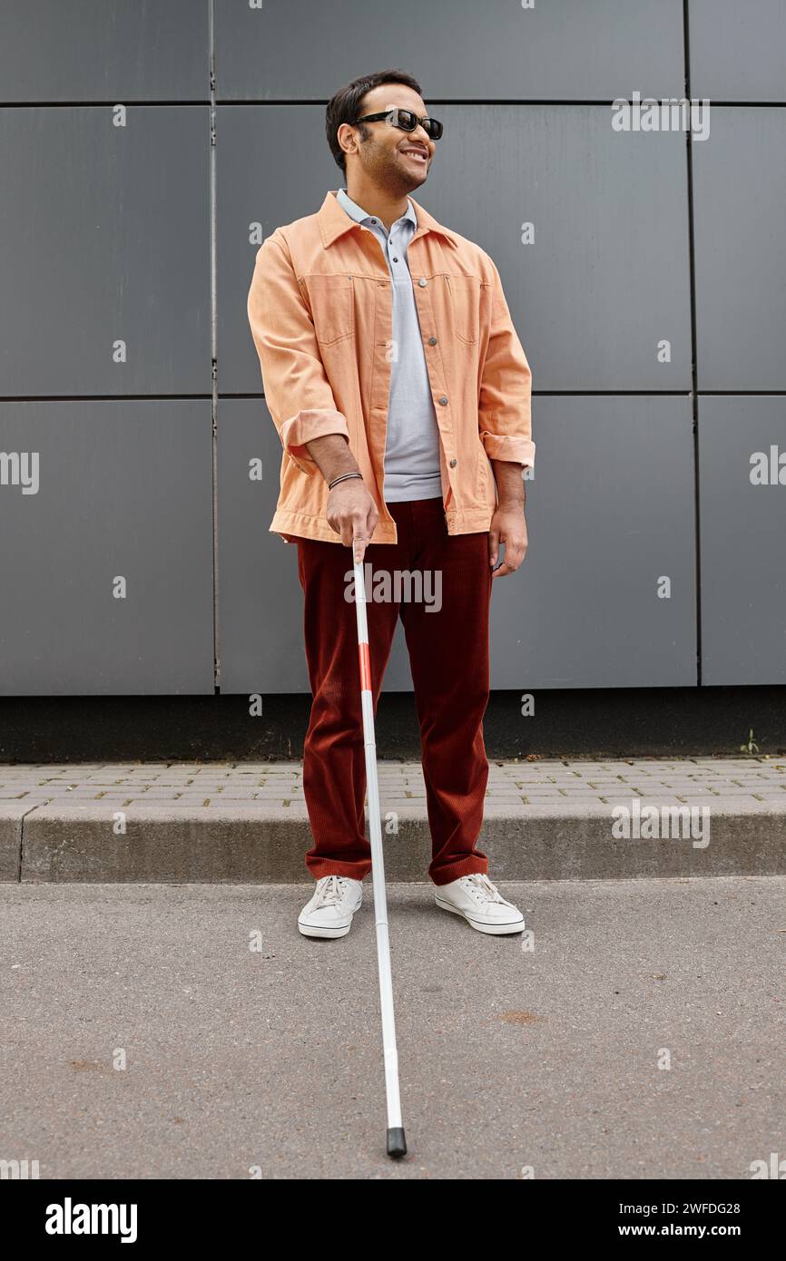 cheerful indian blind man in orange jacket with walking stick and ...