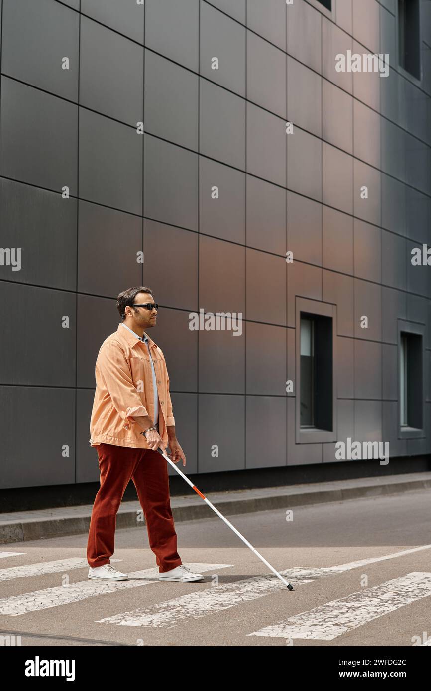 handsome indian disabled man in orange jacket with glasses and stick ...