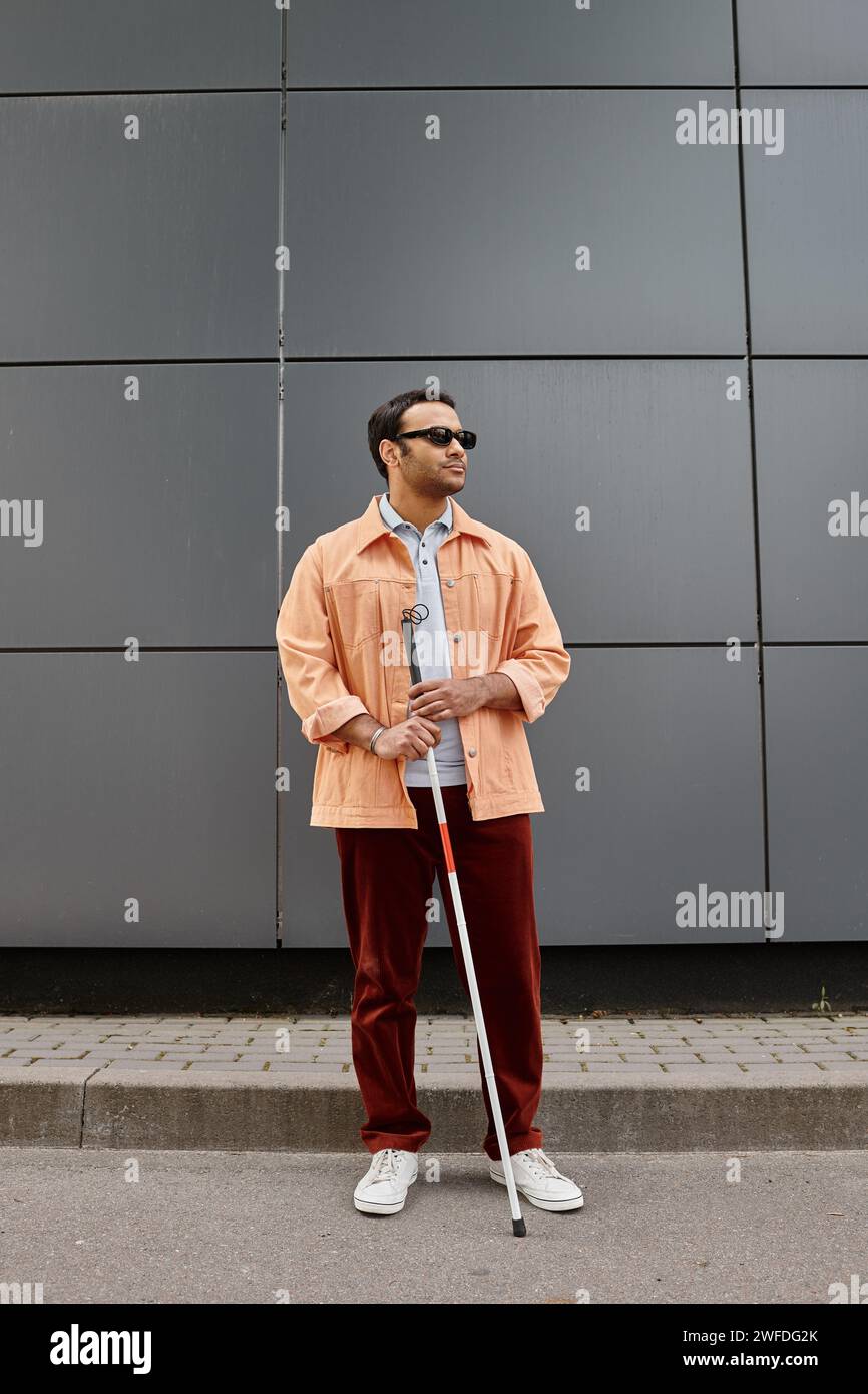 good looking indian disabled man in orange jacket with glasses and ...