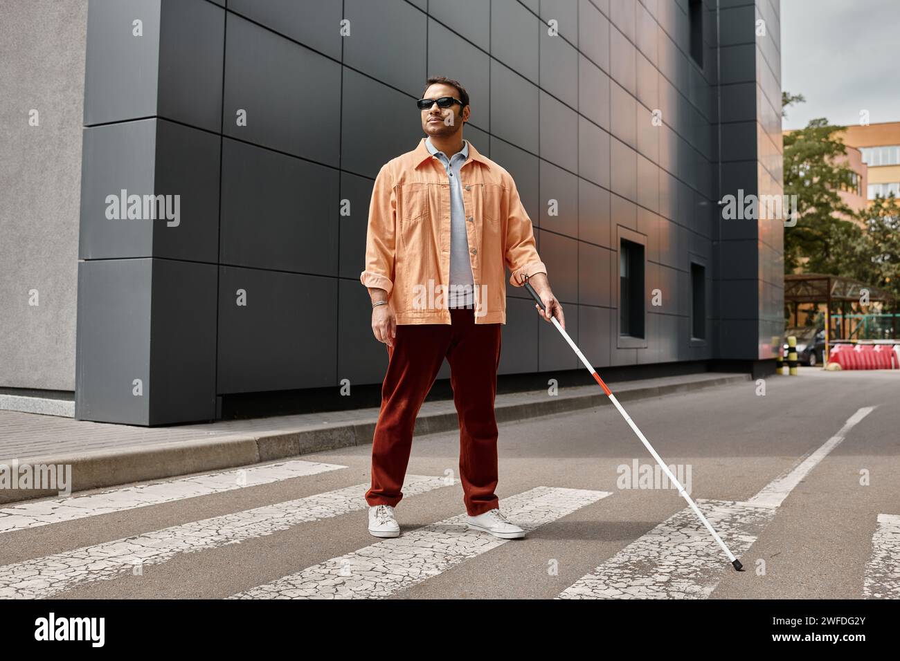 handsome indian blind man in orange jacket with glasses and stick with ...